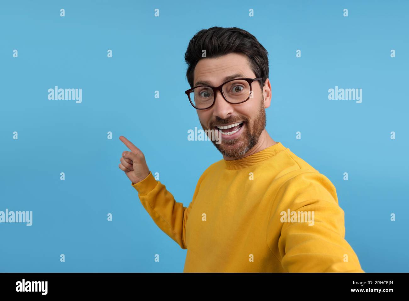 Smiling man taking selfie on light blue background Stock Photo - Alamy