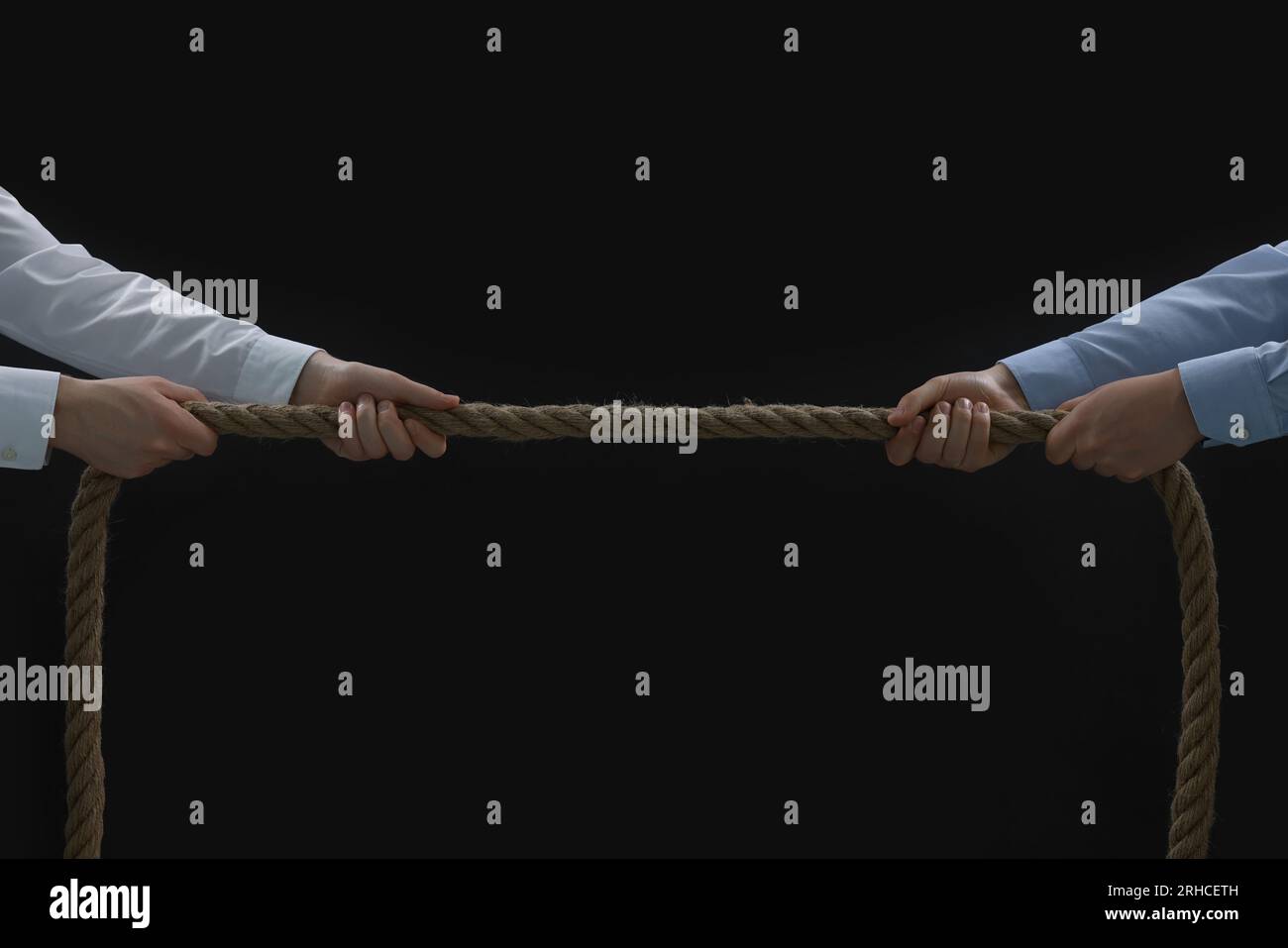 Dispute concept. Men pulling rope on black background, closeup Stock ...