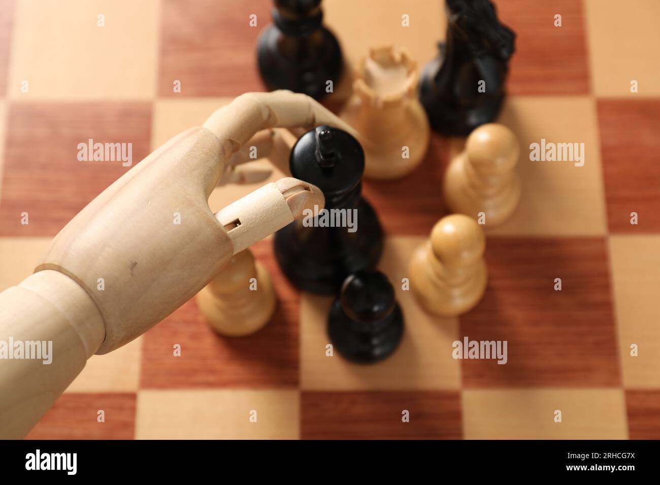 Robot moving chess piece on board, above view. Wooden hand representing ...