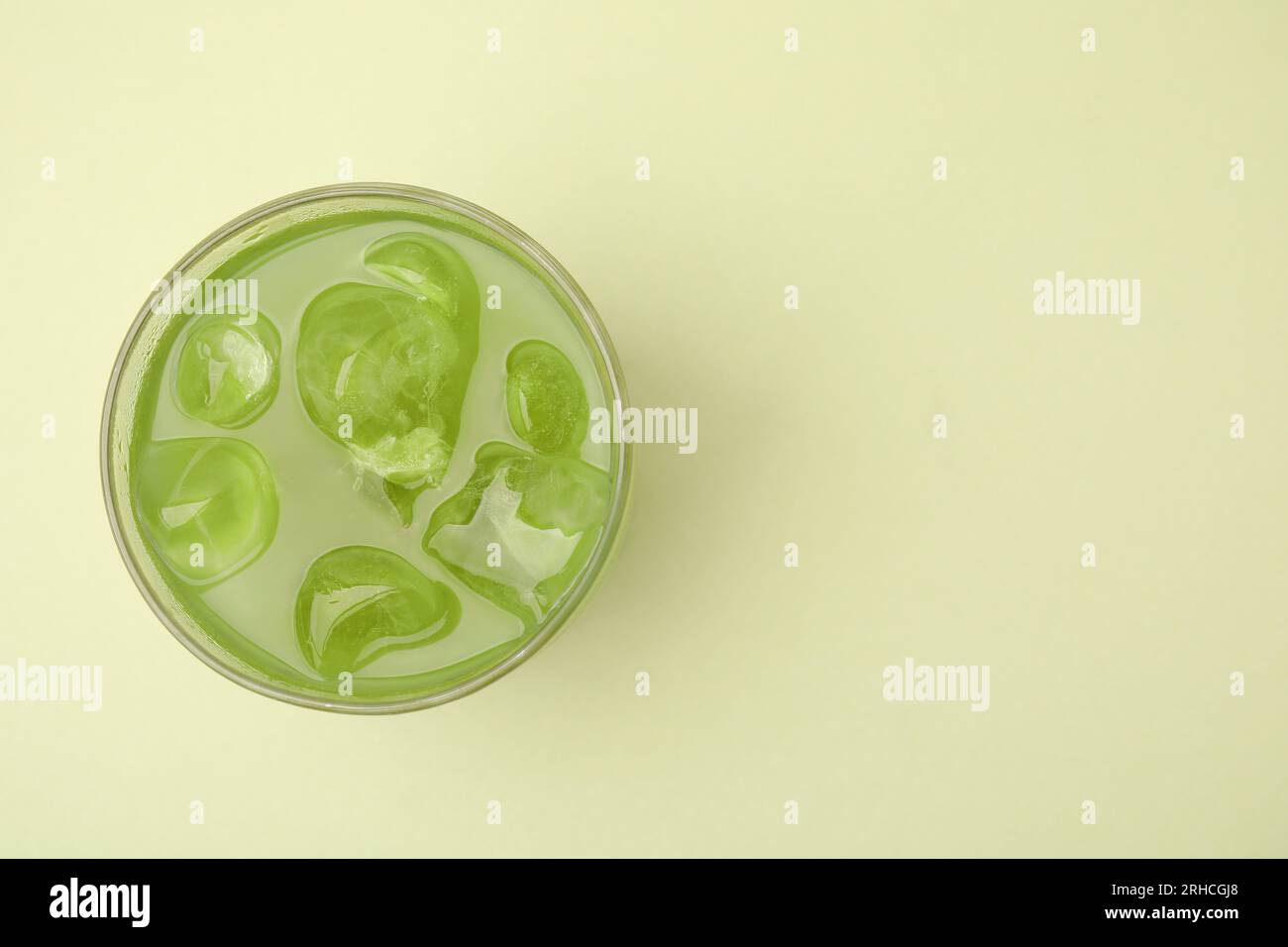 Glass of delicious iced matcha tea on green background, top view. Space ...