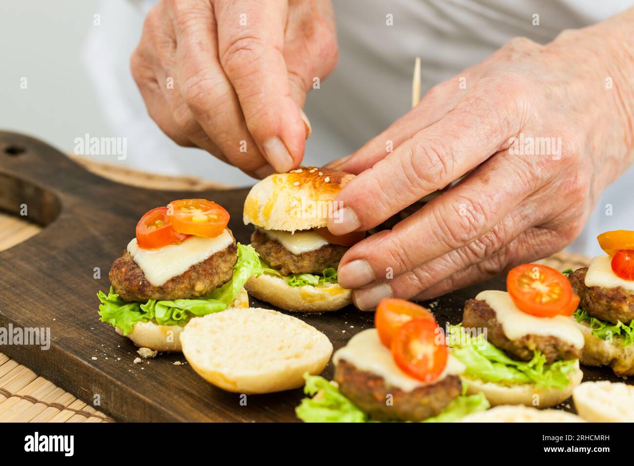 Putting on a toothpick on burger. Step by step preparation of mini ...