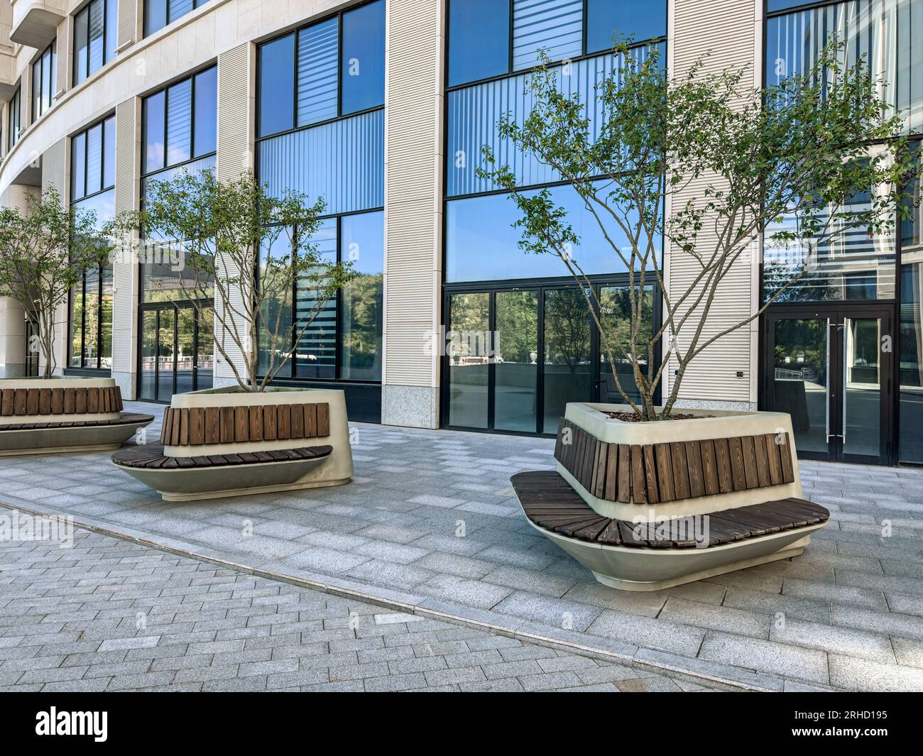 courtyard in an office buildings complex with green trees and benches ...