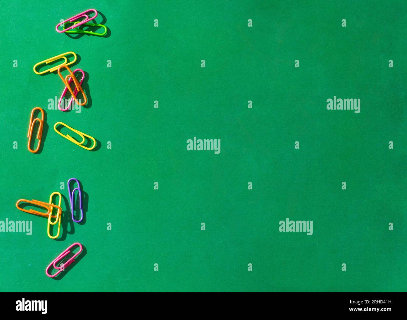 Colorful paper clips on a green background Stock Photo - Alamy