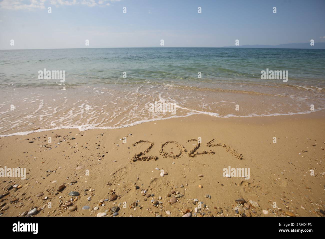 New Year 2024, lettering on the beach with wave and clear blue sea ...