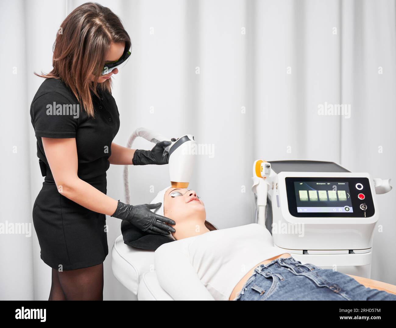 Female beautician using diode laser device while performing facial ...