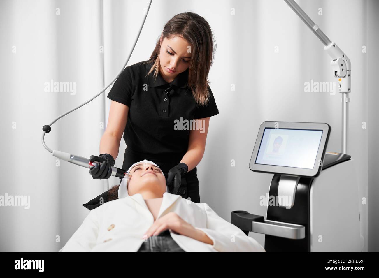 Female cosmetologist using radiofrequency microneedling device while ...