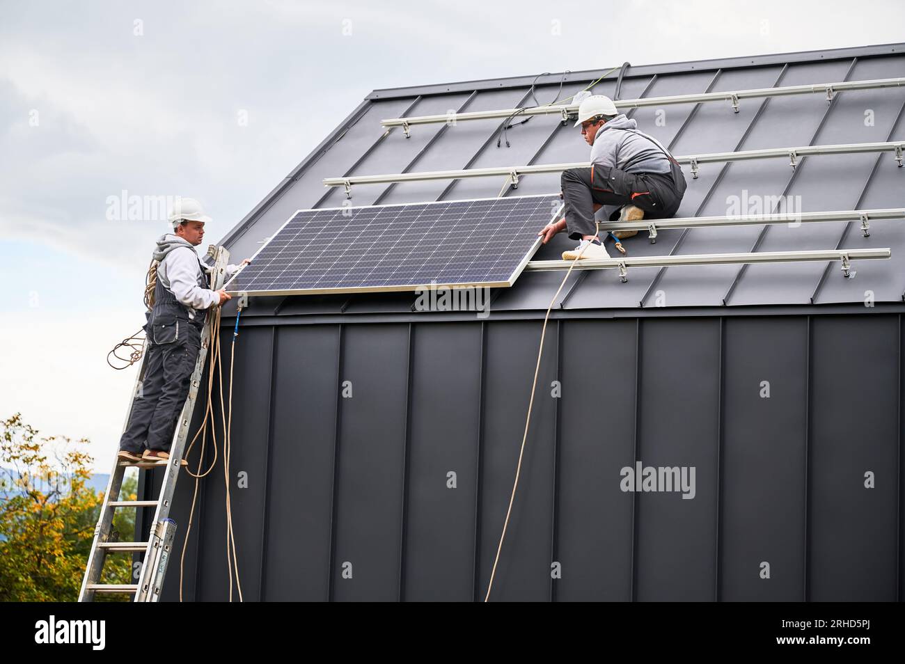 Mounters building photovoltaic solar module station on roof of house ...