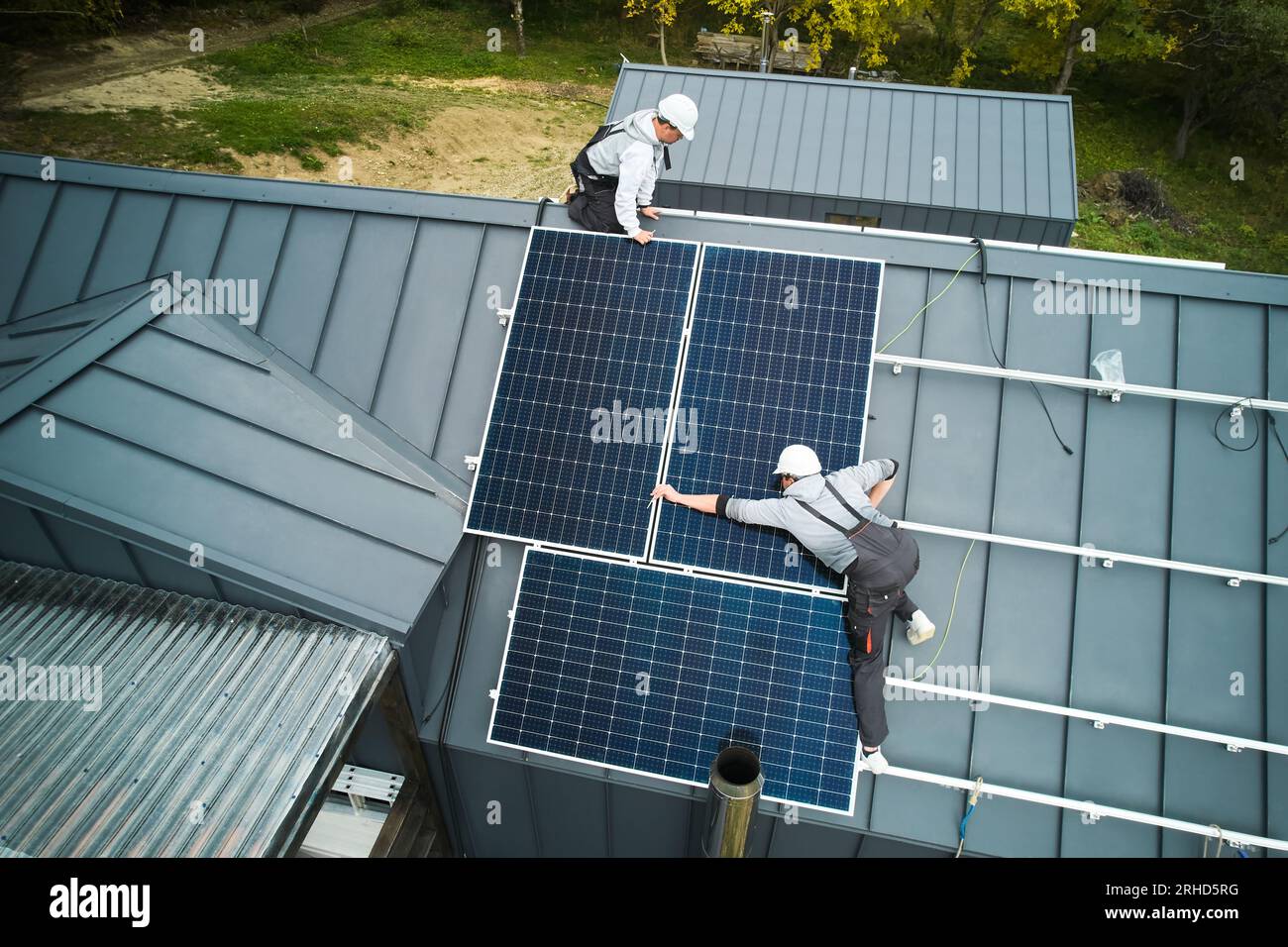 Builders installing photovoltaic solar panels on roof of house. Men ...