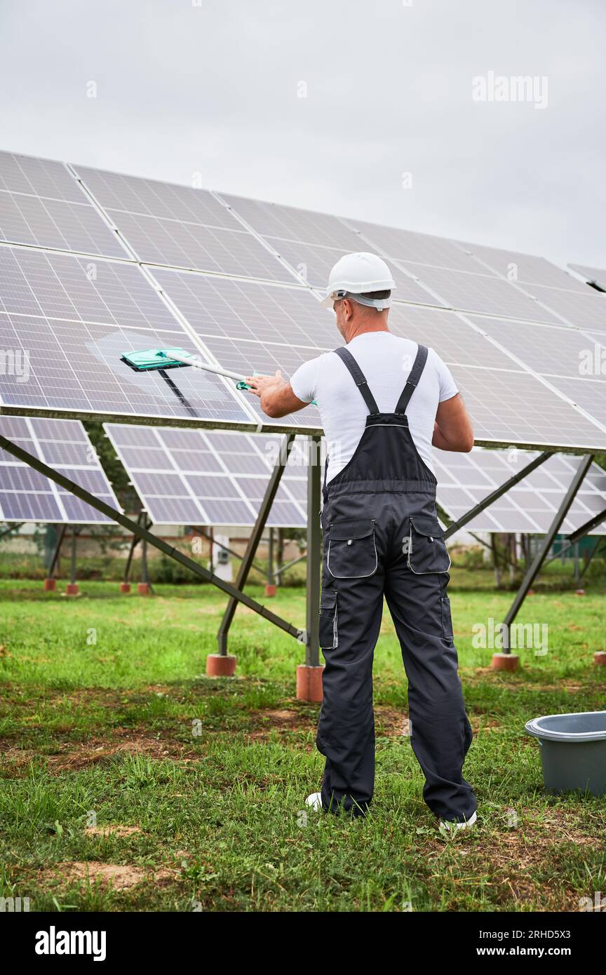 Professional worker cleaning solar PV panel. Man making sure solar ...