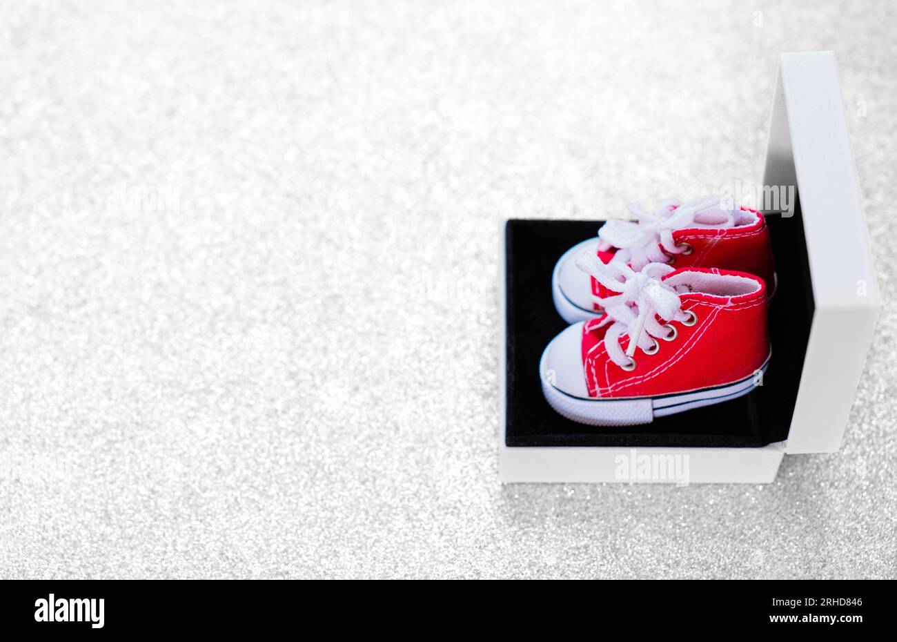 Pair of mini red canvas shoes placed inside a small gift box, set ...