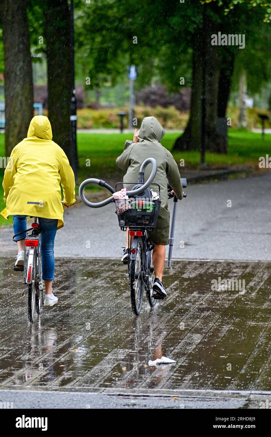 Rides bike through rain with vacuum cleaner in basket Orebro Sweden ...