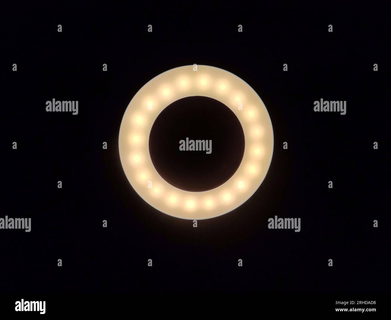 A circular LED light ring with a warm white glow, emitting a soft ...