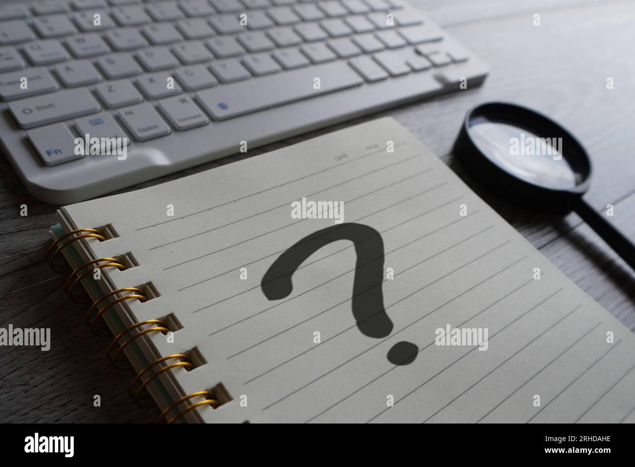 Closeup image of notebook with question mark, magnifying glass and ...