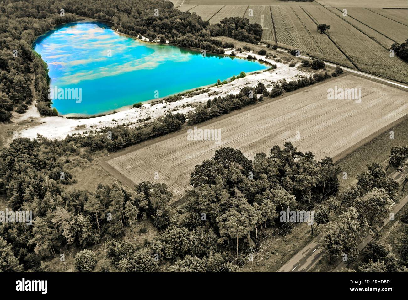 Alienated aerial photograph of a gravel pond between fields and forests ...