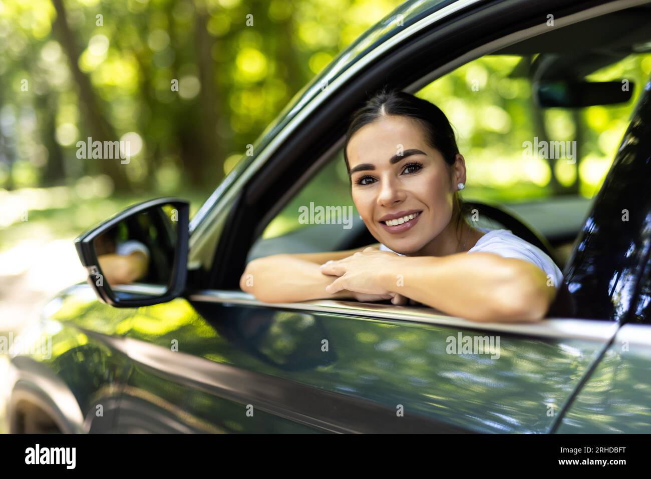 Beautiful young happy smiling woman driving her new car at sunset ...