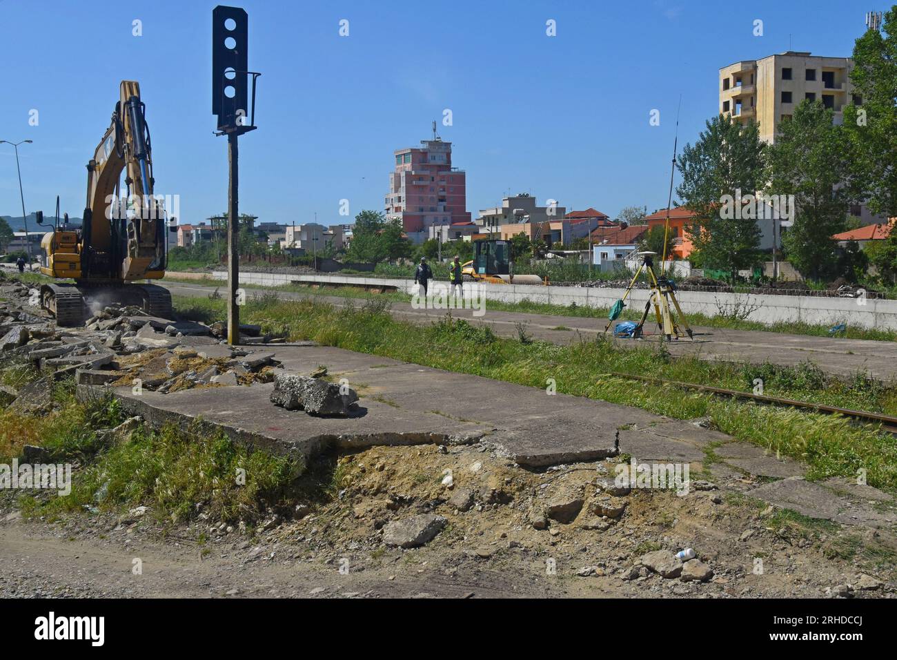 An excavator operating a hydraulic breaker demolishing old platforms ...