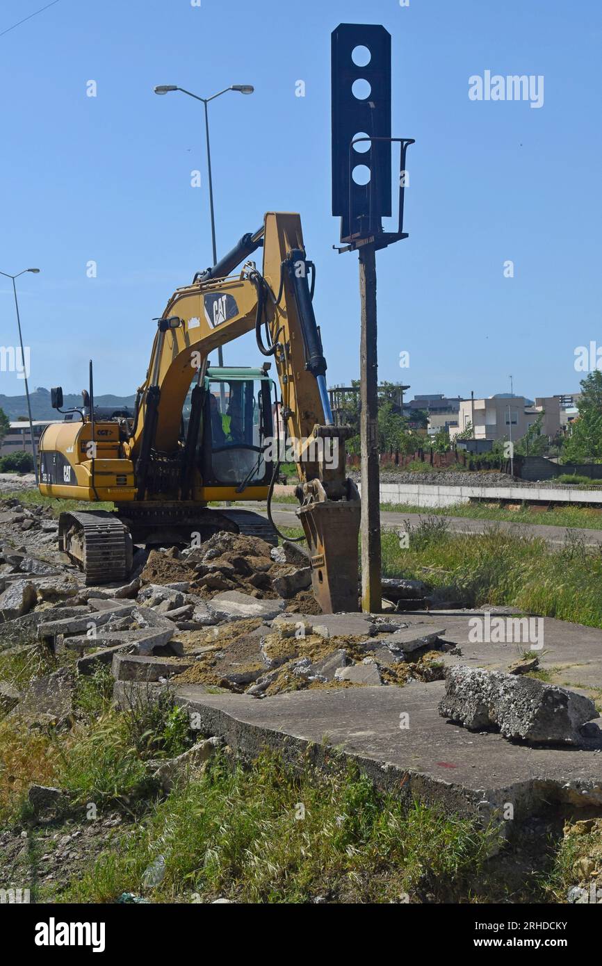 An excavator operating a hydraulic breaker demolishing old platforms ...