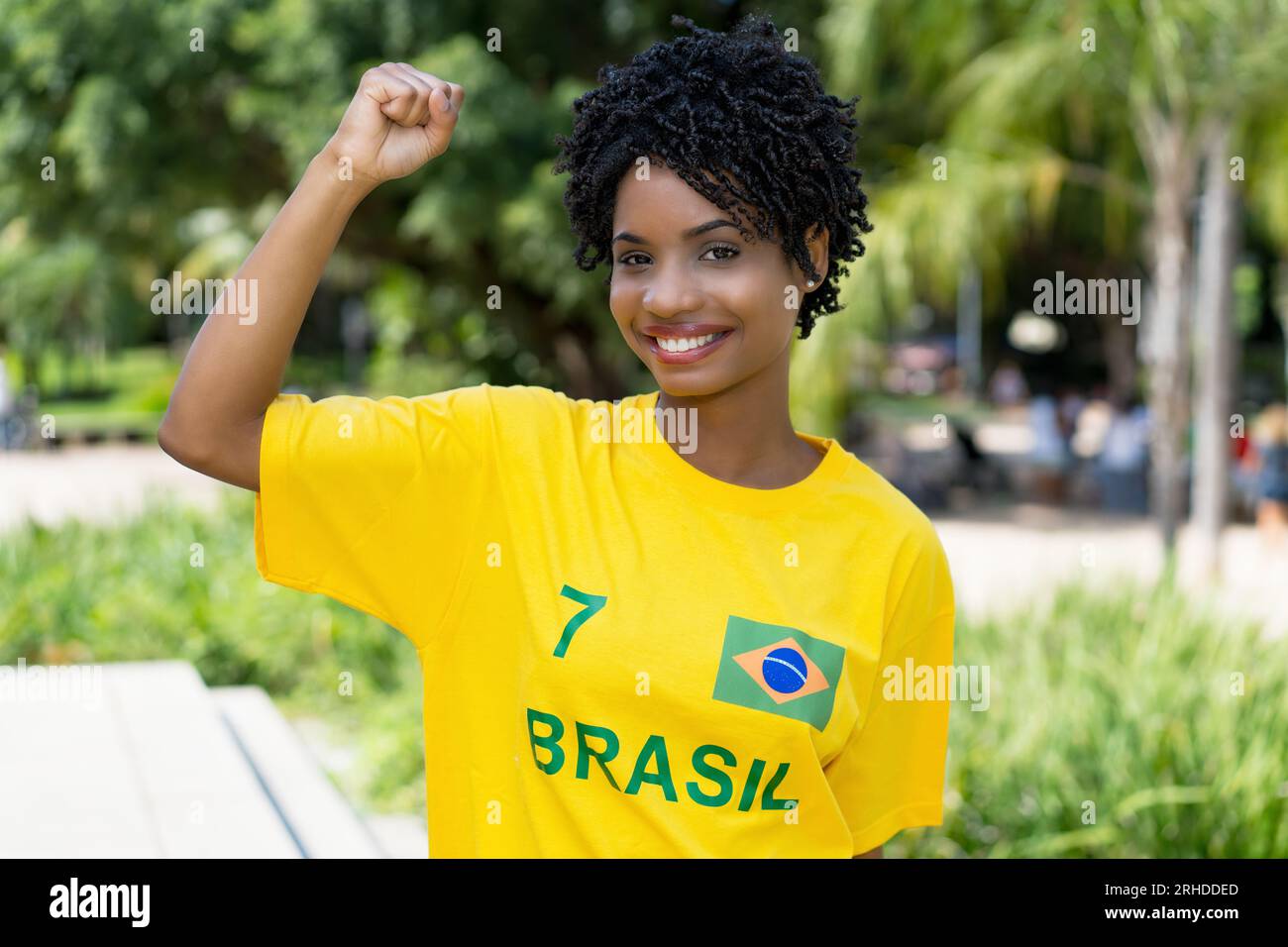 Excited young woman from Brazil with yellow football jersey outdoors in ...