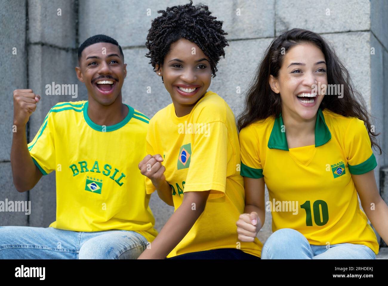 Group of cheering football fans from Brazil with yellow soccer outdoors ...
