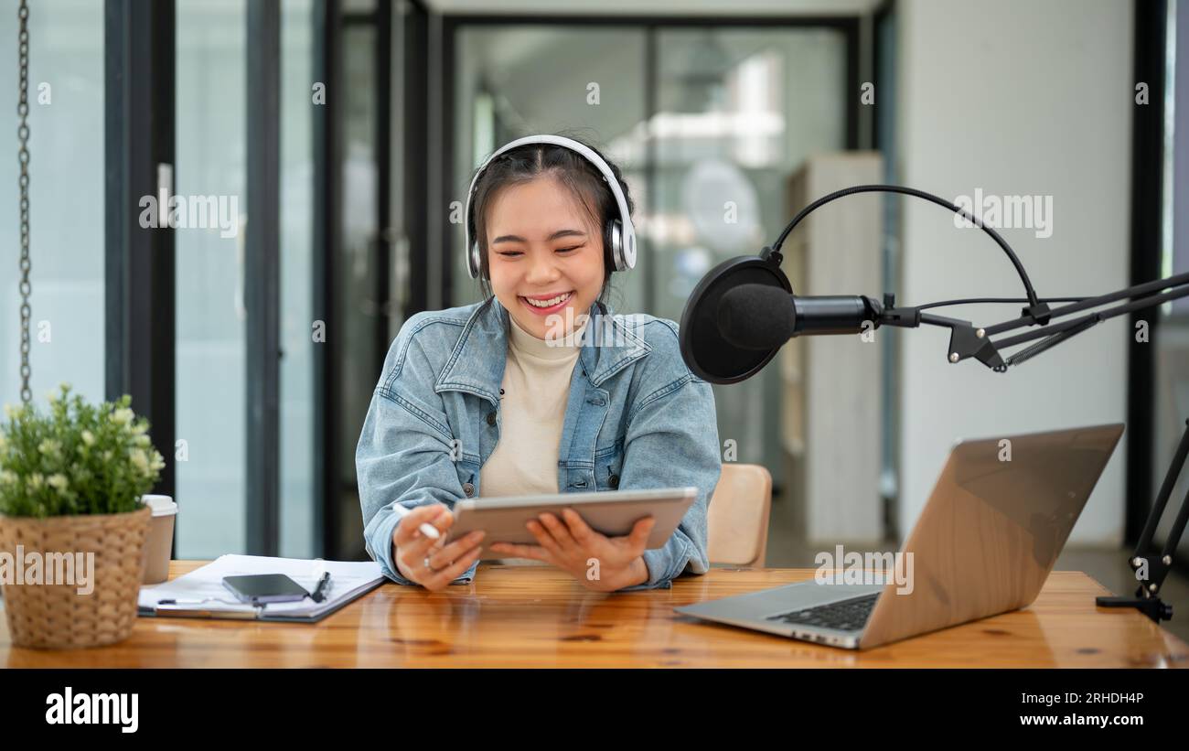 A beautiful and cheerful Asian female radio host or podcaster is ...