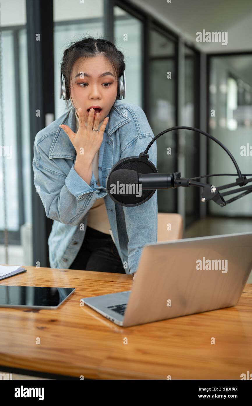 A shocked and stunned Asian female radio host or radio journalist is ...