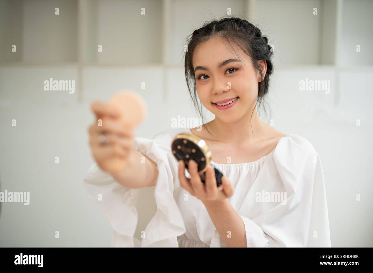 An attractive Asian female beauty influencer applying her makeup, showing her new cosmetic ...