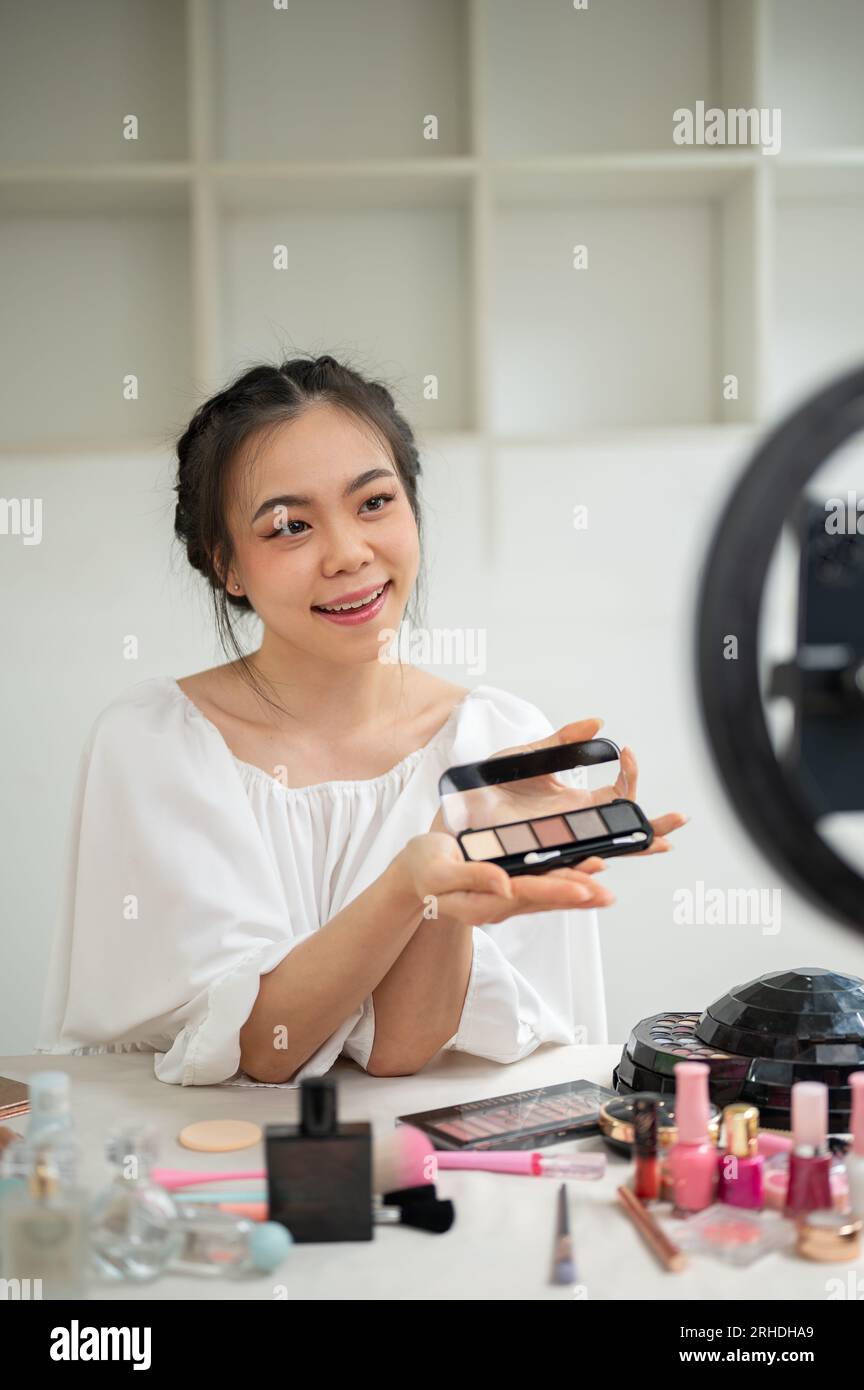A beautiful Asian female beauty influencer is speaking to the camera ...
