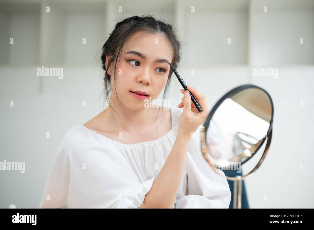 A beautiful and pretty Asian female looks in the mirror and draws her ...