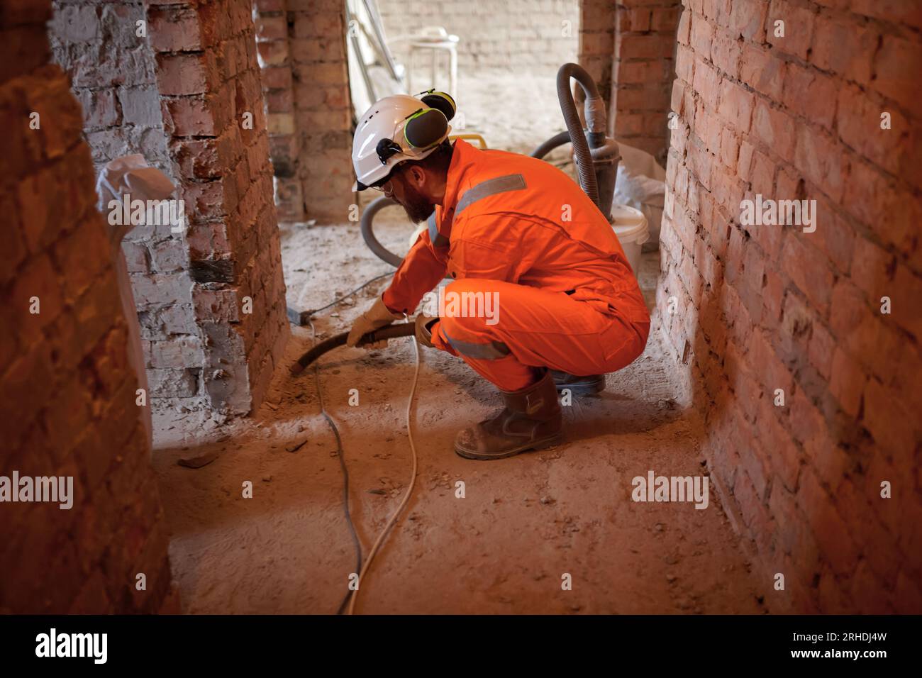 Constriction site worker cleaning concrete floor with special vacuum ...