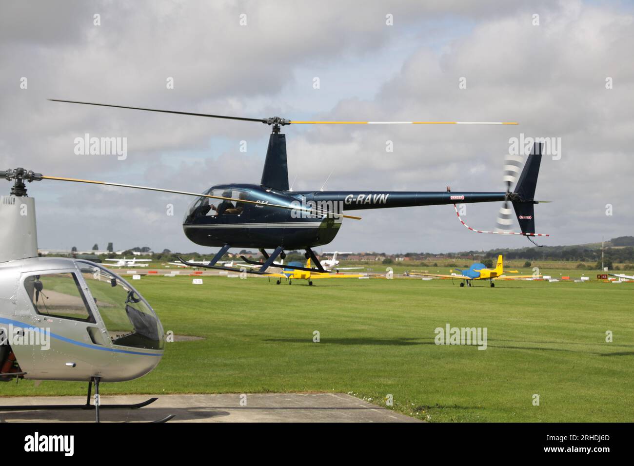 A Robinson R44 helicopter lands behind a Robinson R22 at Brighton City ...