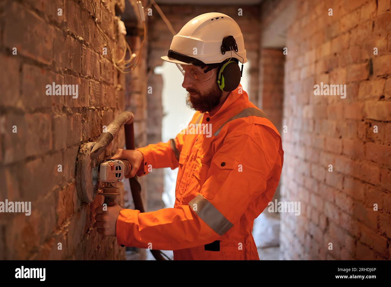 Construction worker grinding brick wall using grinding machine with ...