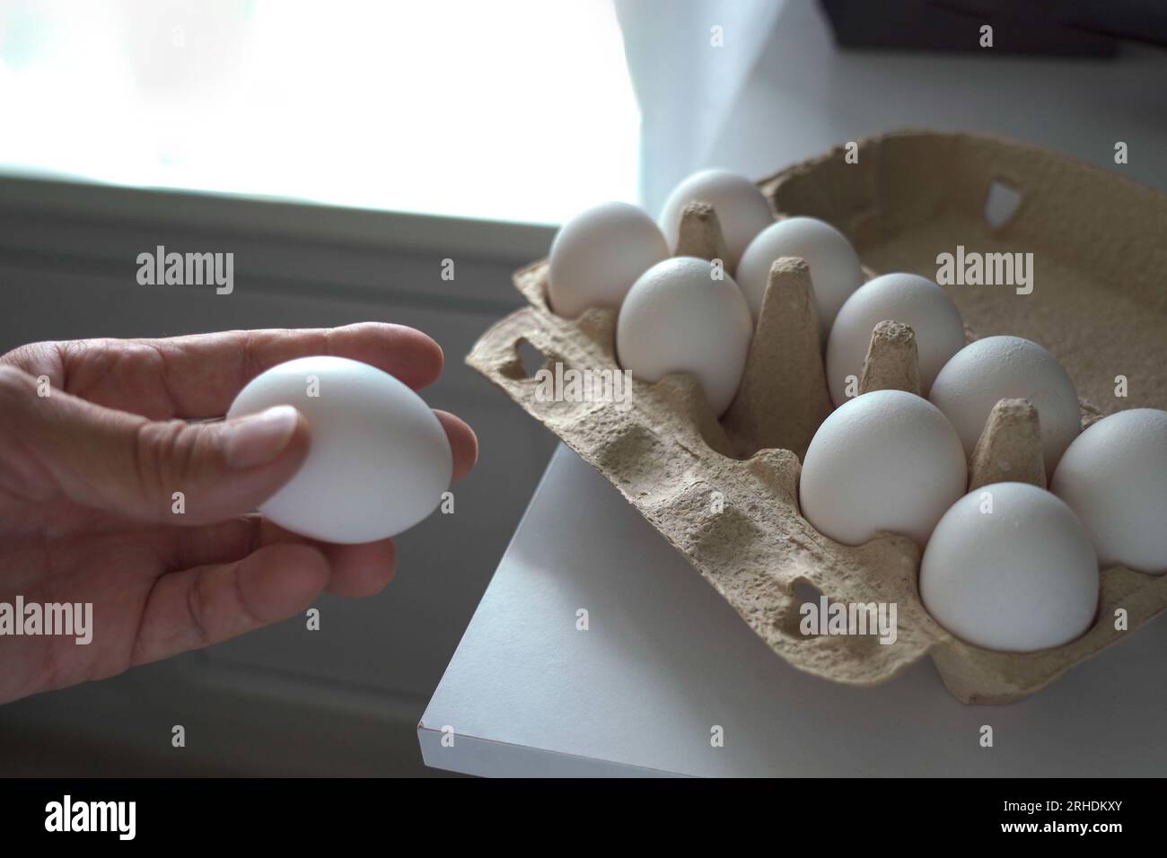 The old man's hands take chicken eggs from the container to cook food ...