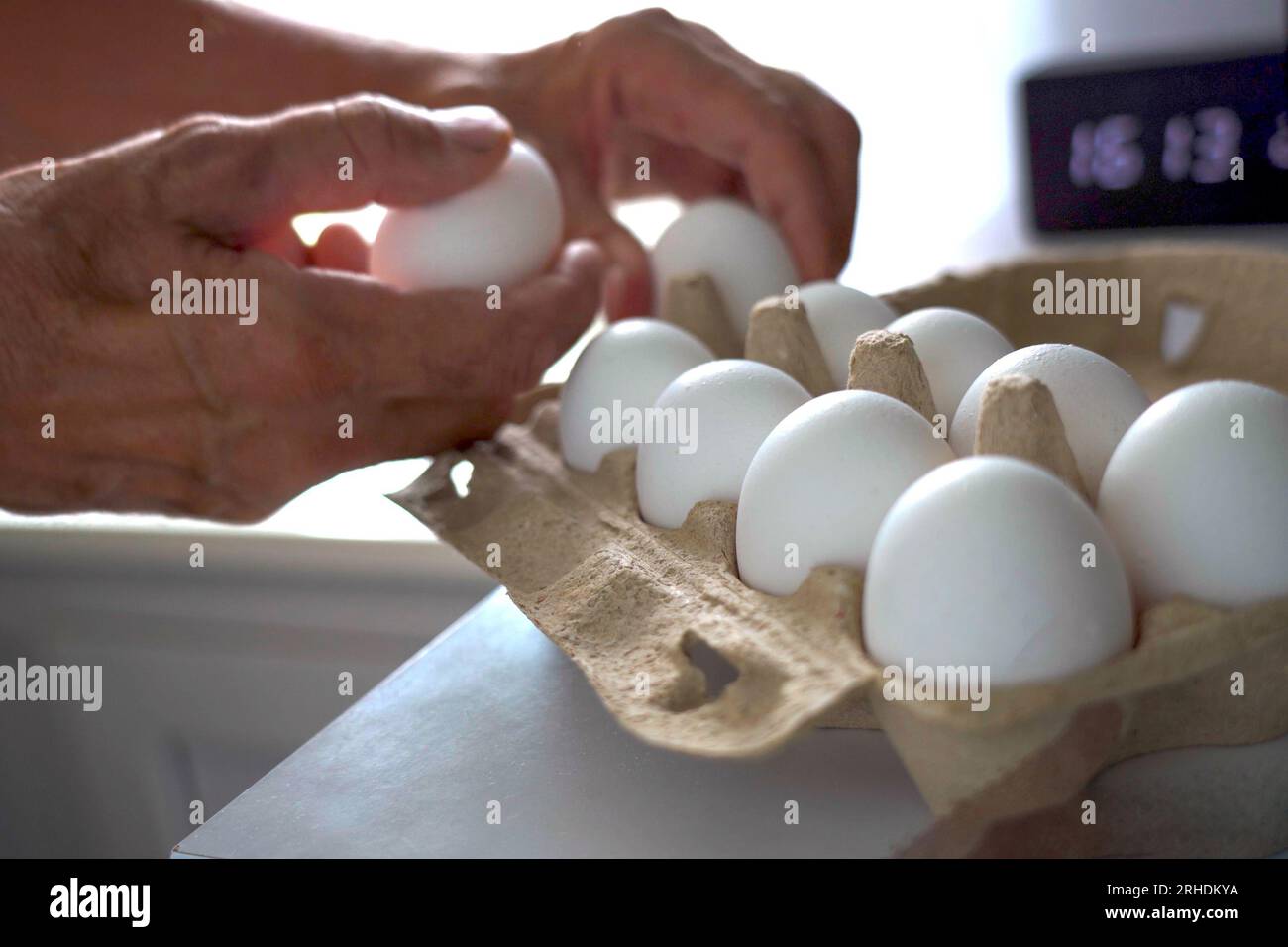 The old man's hands take chicken eggs from the container to cook food ...