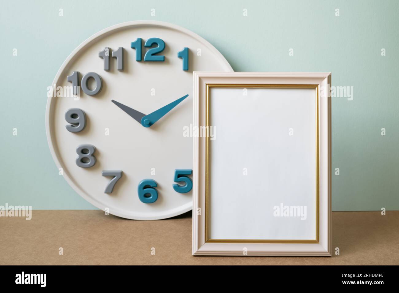 Blank picture frame with clock on brown shelf. mint wall background ...