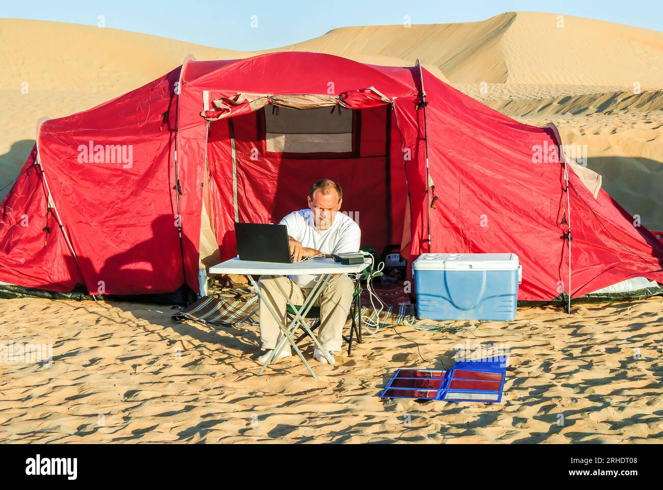 Man is working with his laptop and a portable folding solar kit charger ...