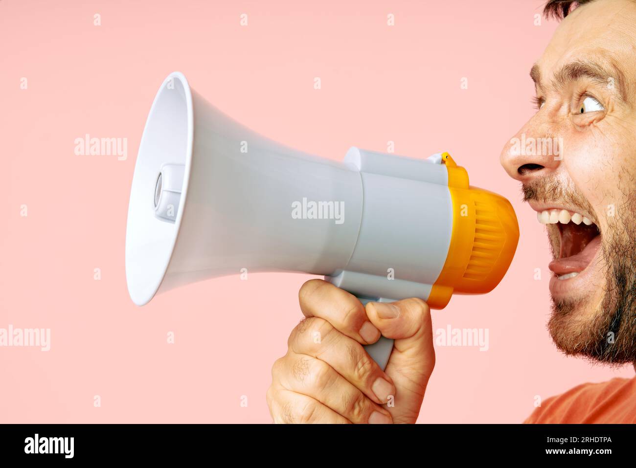 Funny man screaming in megaphone with copy space on pink background ...