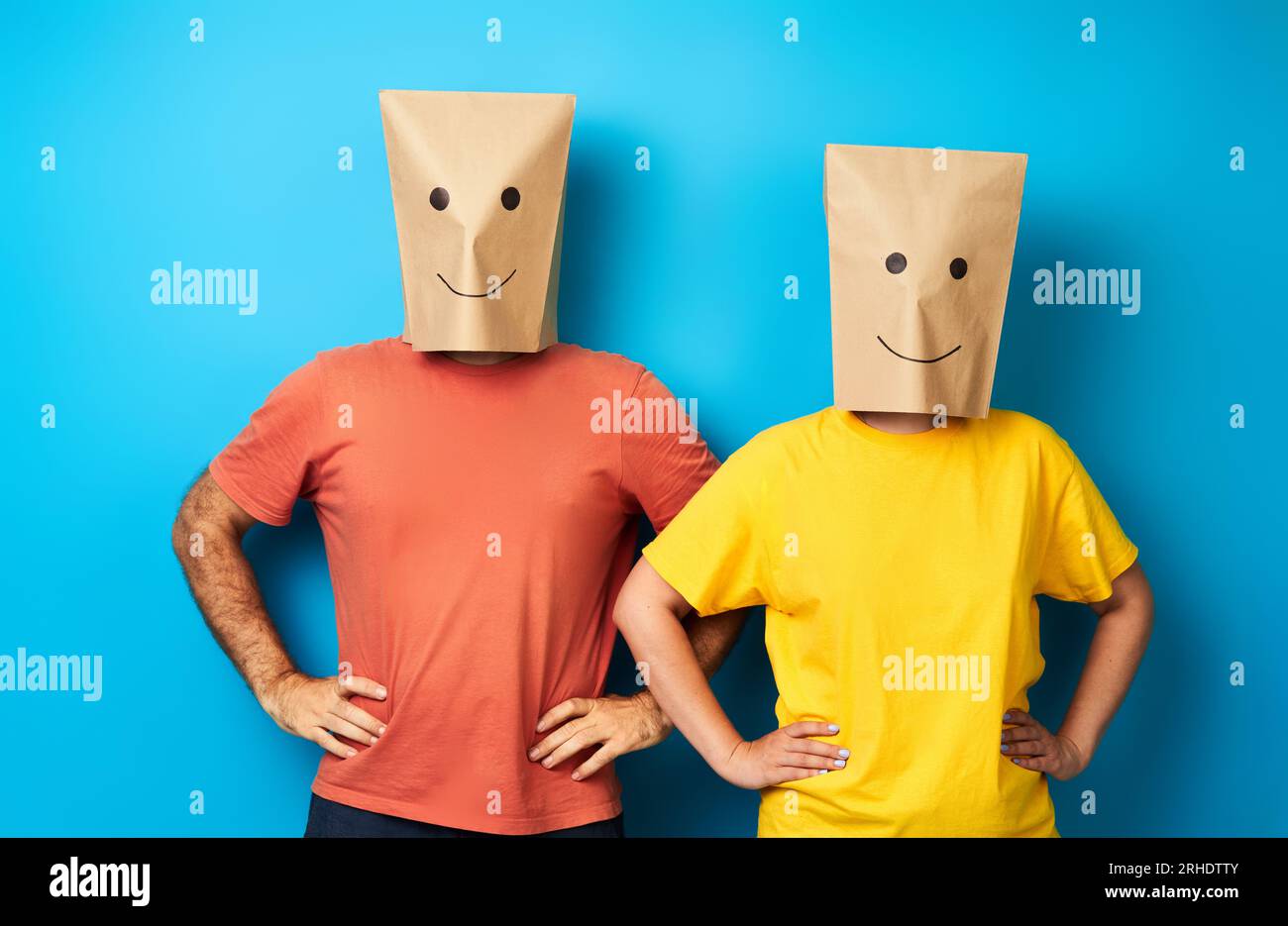 Happy smiling couple with bags over heads posing over blue studio ...