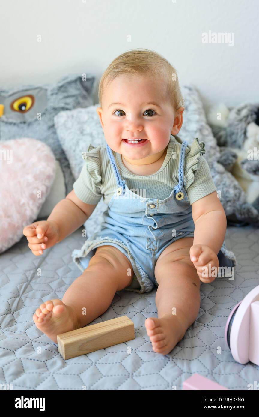 Full body of playful little baby near wooden toy block sitting on soft ...