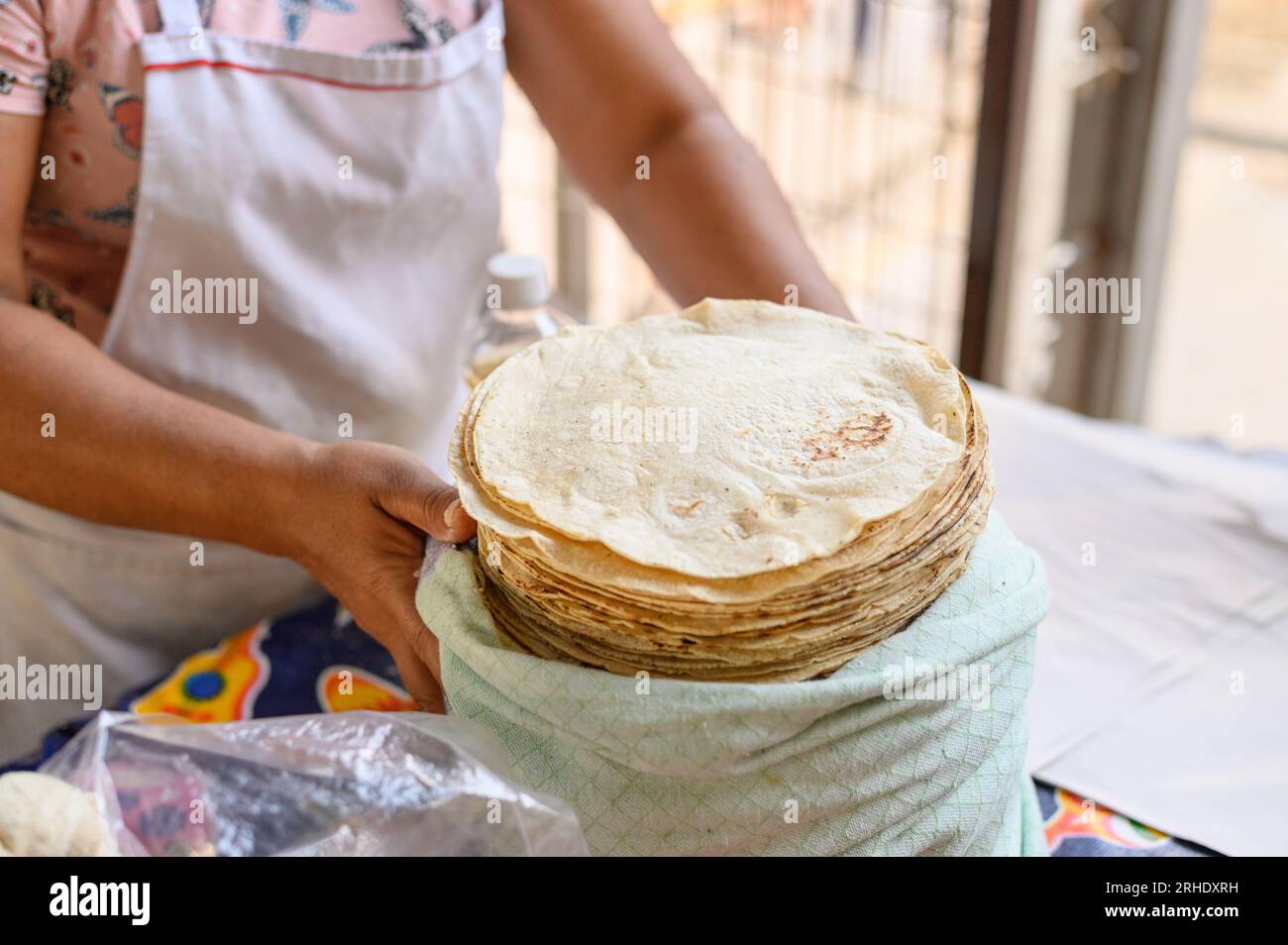 From above of crop anonymous female baker in apron standing with stack ...