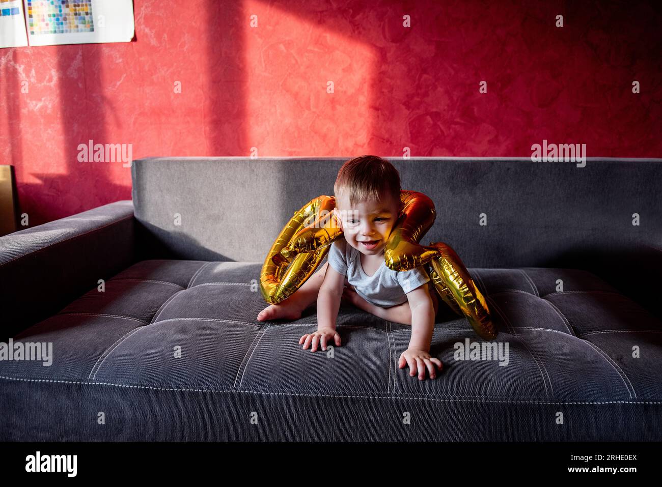 First birthday party, baby plays with gold colored foil balloons ONE ...