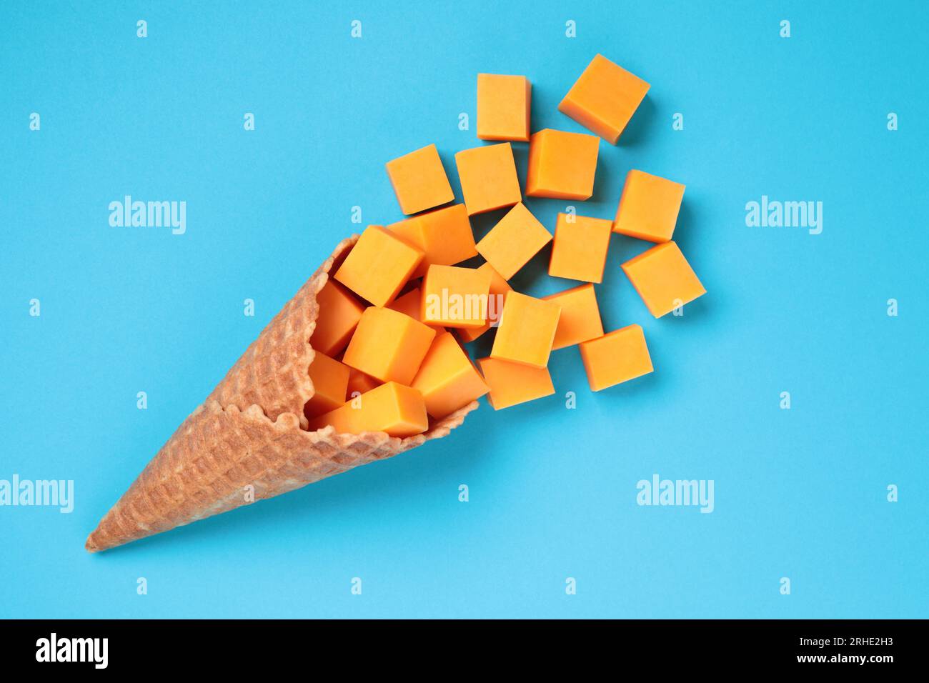 Waffle Cone with Yellow Cheese Cubes on blue background close-up Stock ...