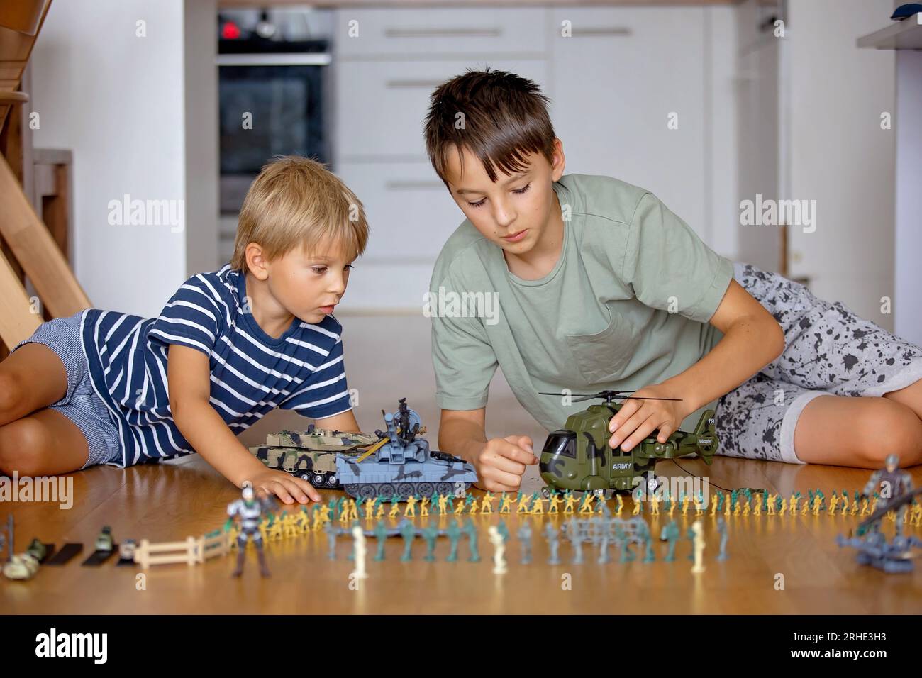 Happy children, siblings, boy, playing with tanks and soldiers at home ...