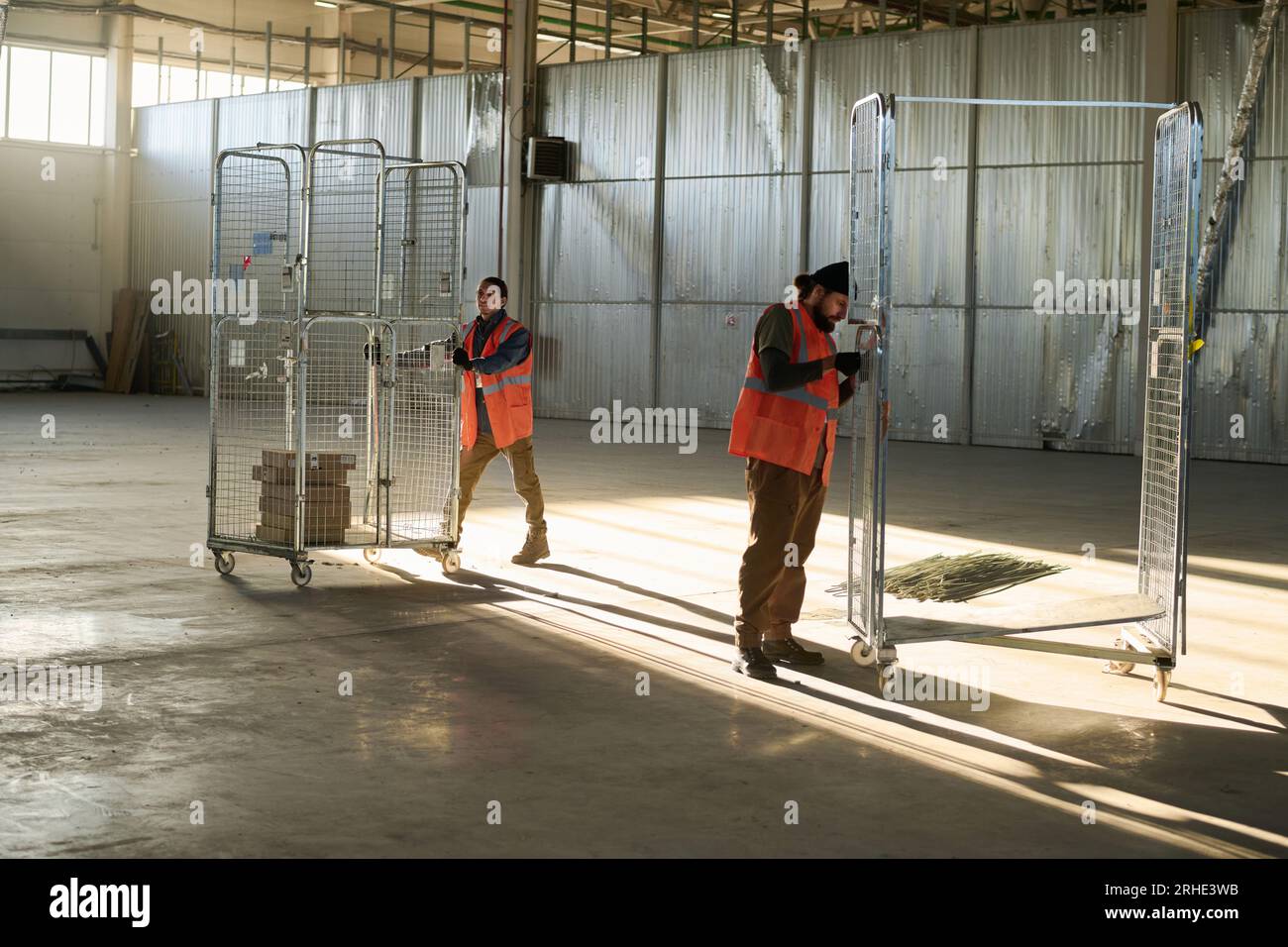 Long shot of two young male engineers in workear pushing and repairing ...