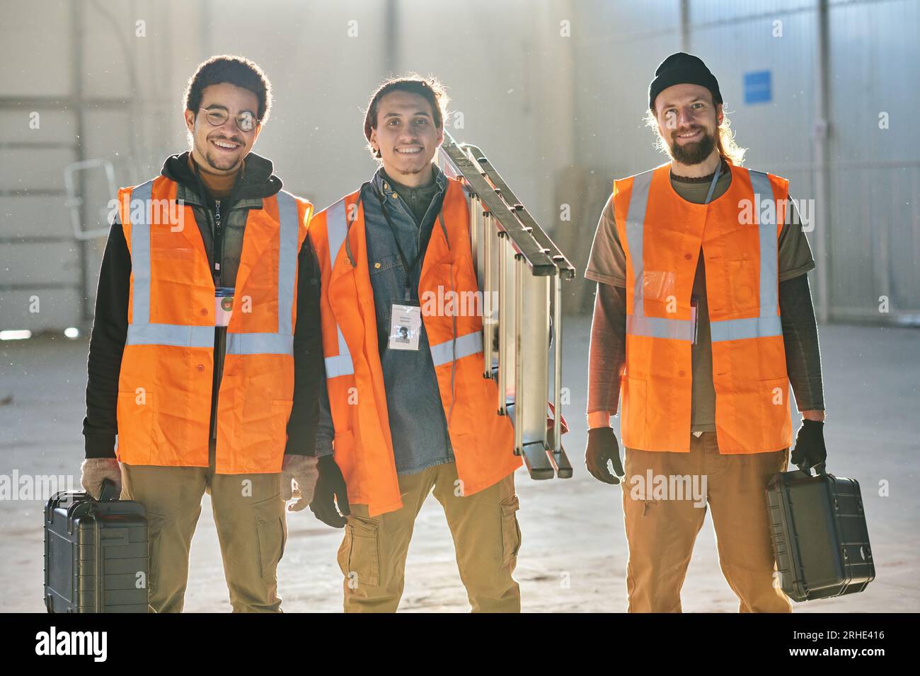 Group of young successful engineers of industrial plant or warehouse ...