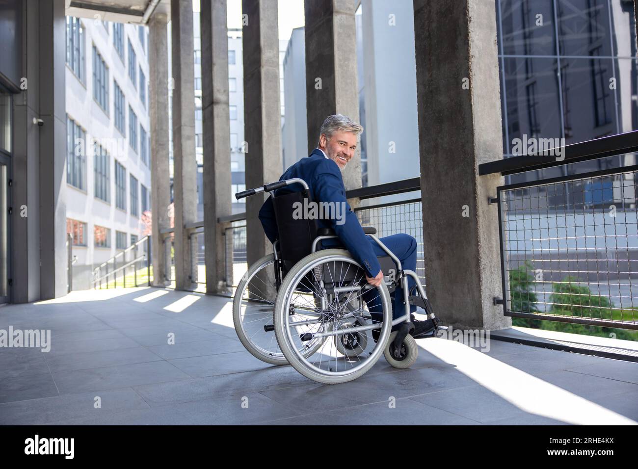 Gray haired disabled man wearing official style suit in wheelchair city ...