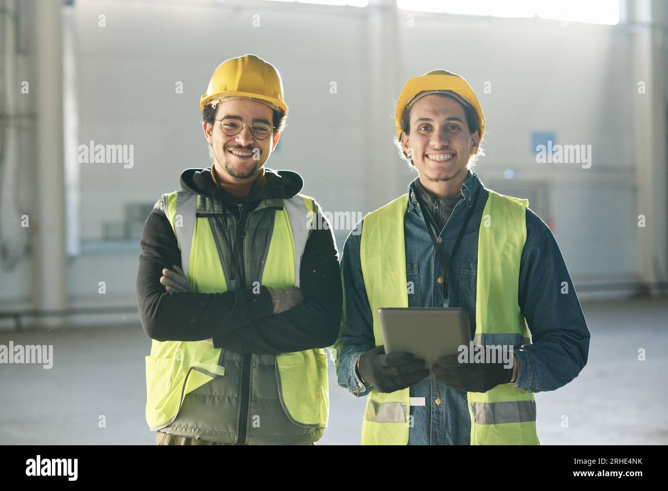 Two happy young multiethnic engineers in hardhats and reflective ...