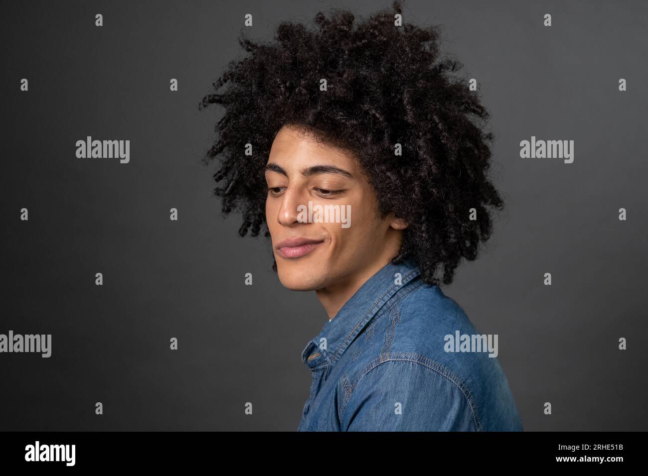 Curly-haired young guy smirking and looking foxy Stock Photo - Alamy
