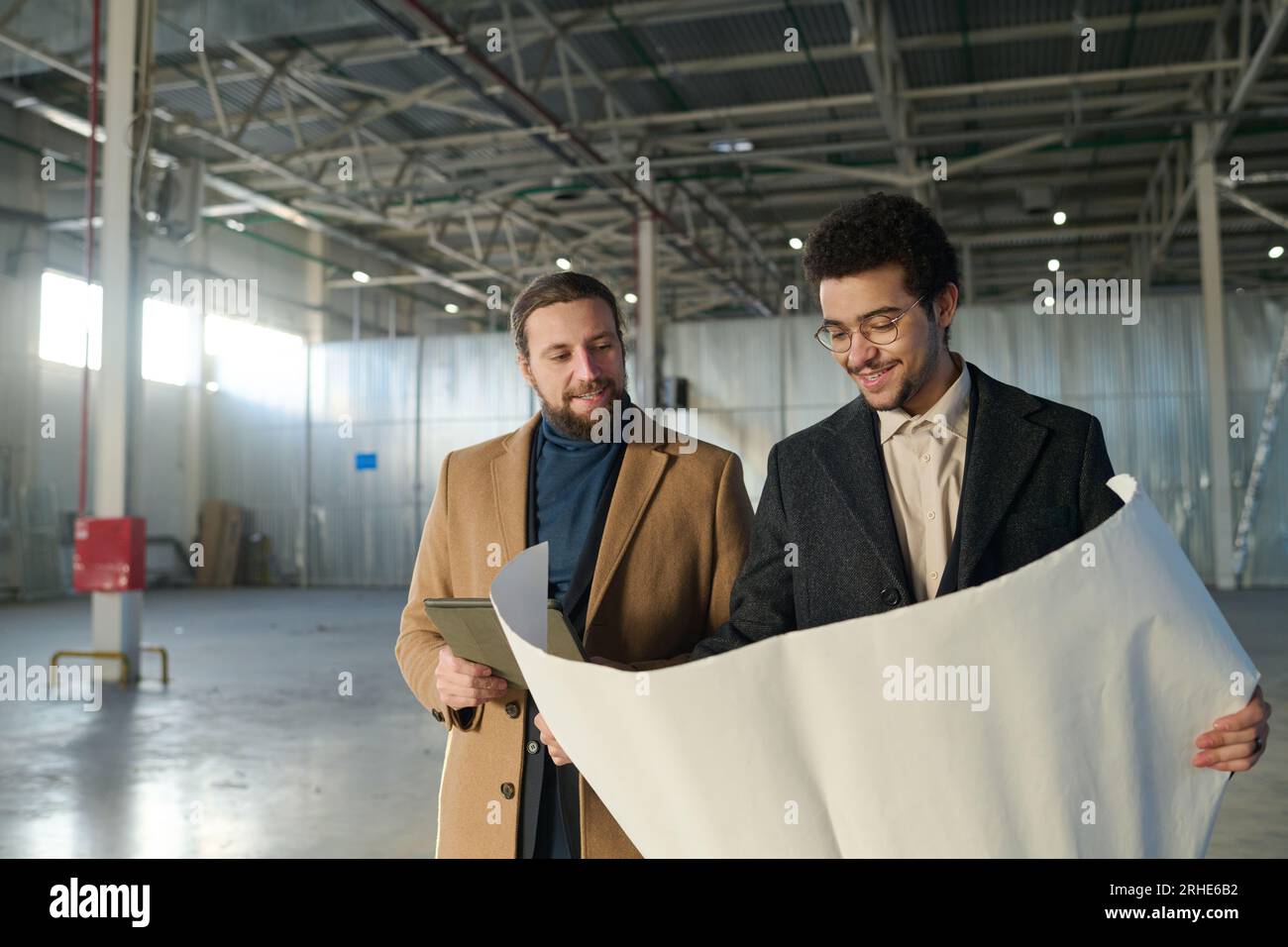 Two young successful directors of business companies looking at sketch ...