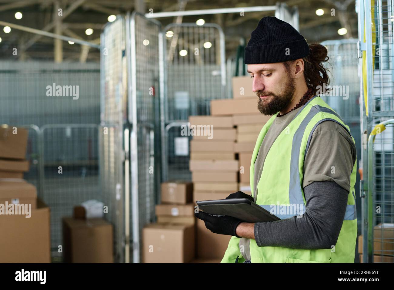 Side view of bearded worker of warehouse in reflective vest looking ...