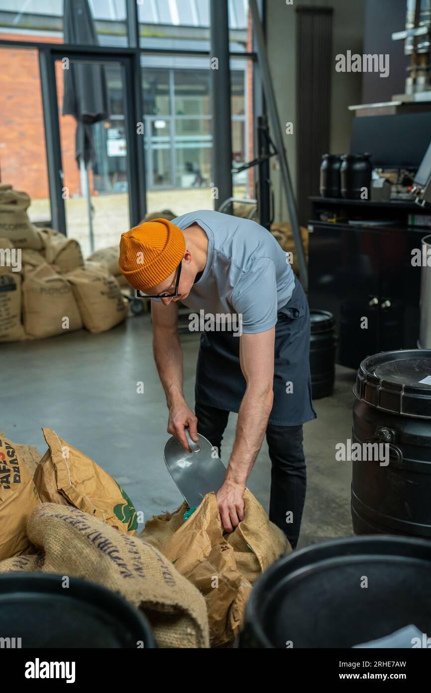 Roasting factory worker working, pouring coffee Stock Photo - Alamy